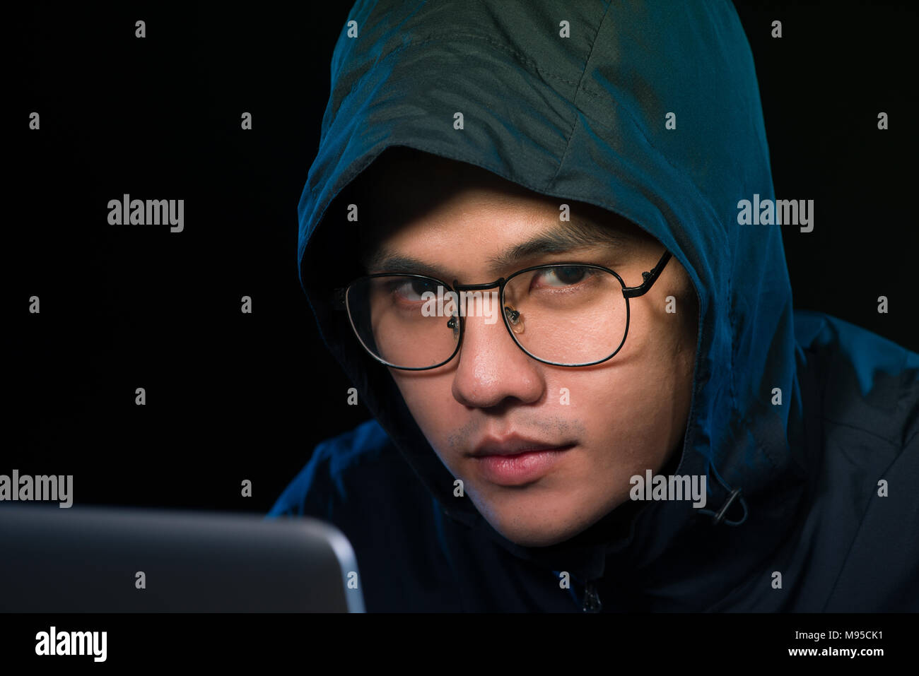 Asian Hacker Hacking Computer Network With Laptop In Dark Cyber