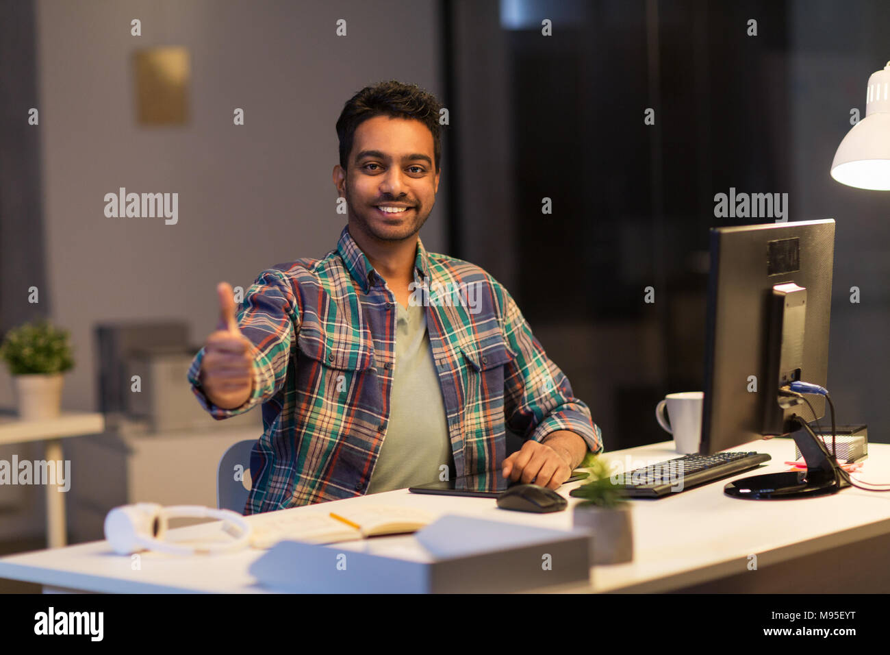 creative man showing thumbs up at night office Stock Photo - Alamy