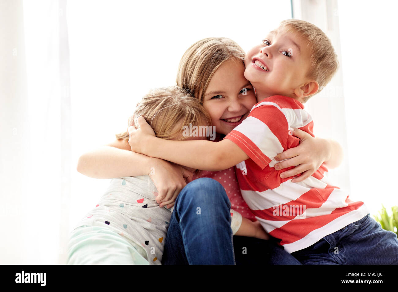 happy little kids hugging at window Stock Photo - Alamy