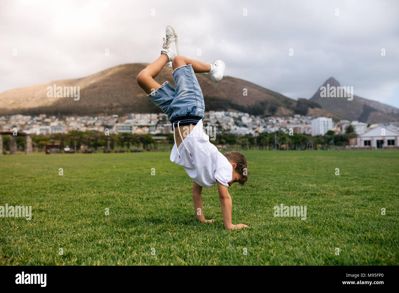 Boy balancing on hands in upside down position in a ground. Boy playing ...