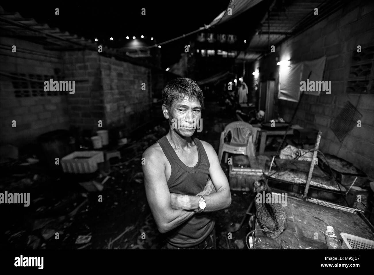 A man stands sullen faced in the street outside his ramshackle home in ...