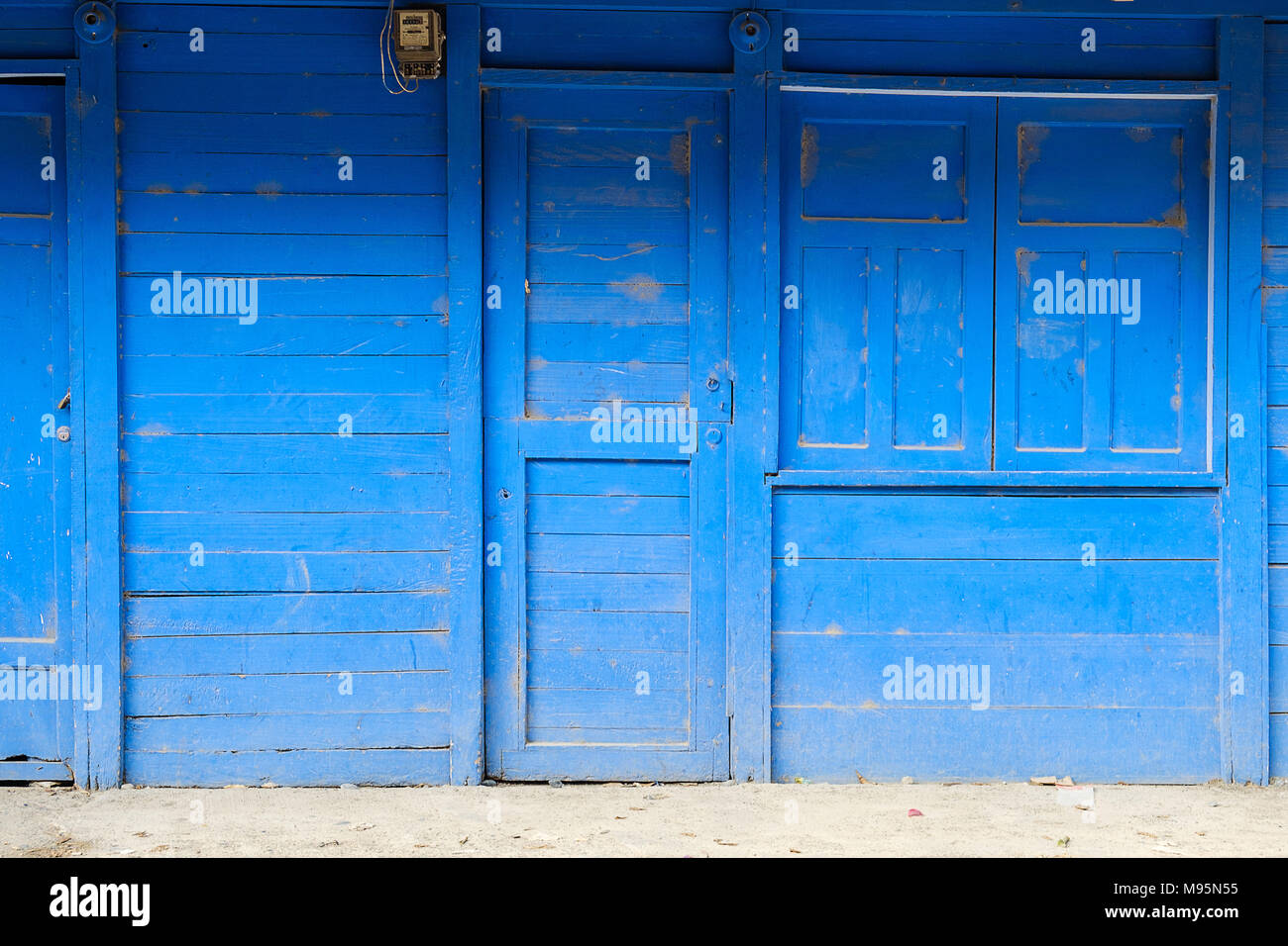 front view of a blue painted wooden house with closed door , window and ...