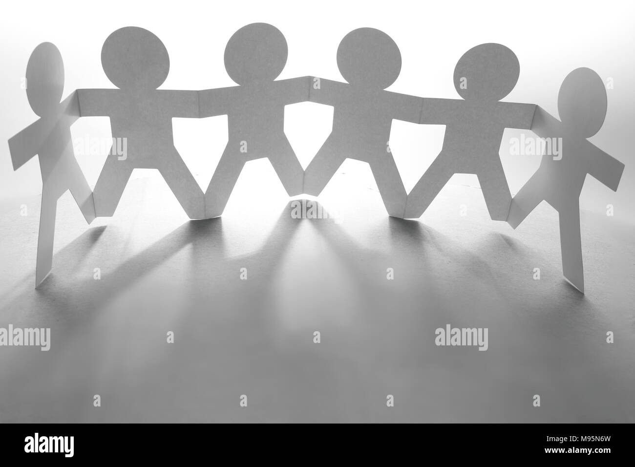 Team of paper chain people in a row holding hands Stock Photo - Alamy