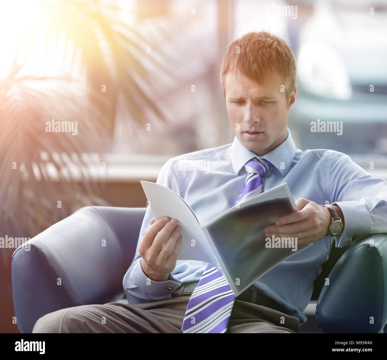 Businessman reading magazine in waiting room Stock Photo - Alamy