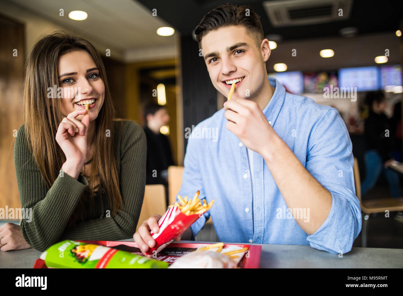 Couple in a restaurant or diner eating a hamburger and potato fries ...