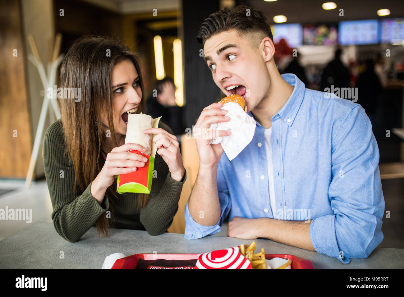 Young couple in a fast food restaurant eating hamburger Stock Photo - Alamy