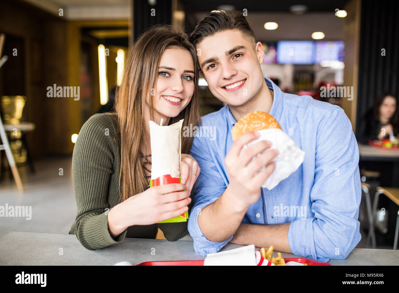 Happy loving couple enjoying and eating fast food Stock Photo - Alamy