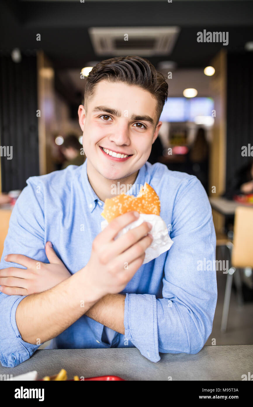 Happy handsome man eating burger in restaurant Stock Photo - Alamy