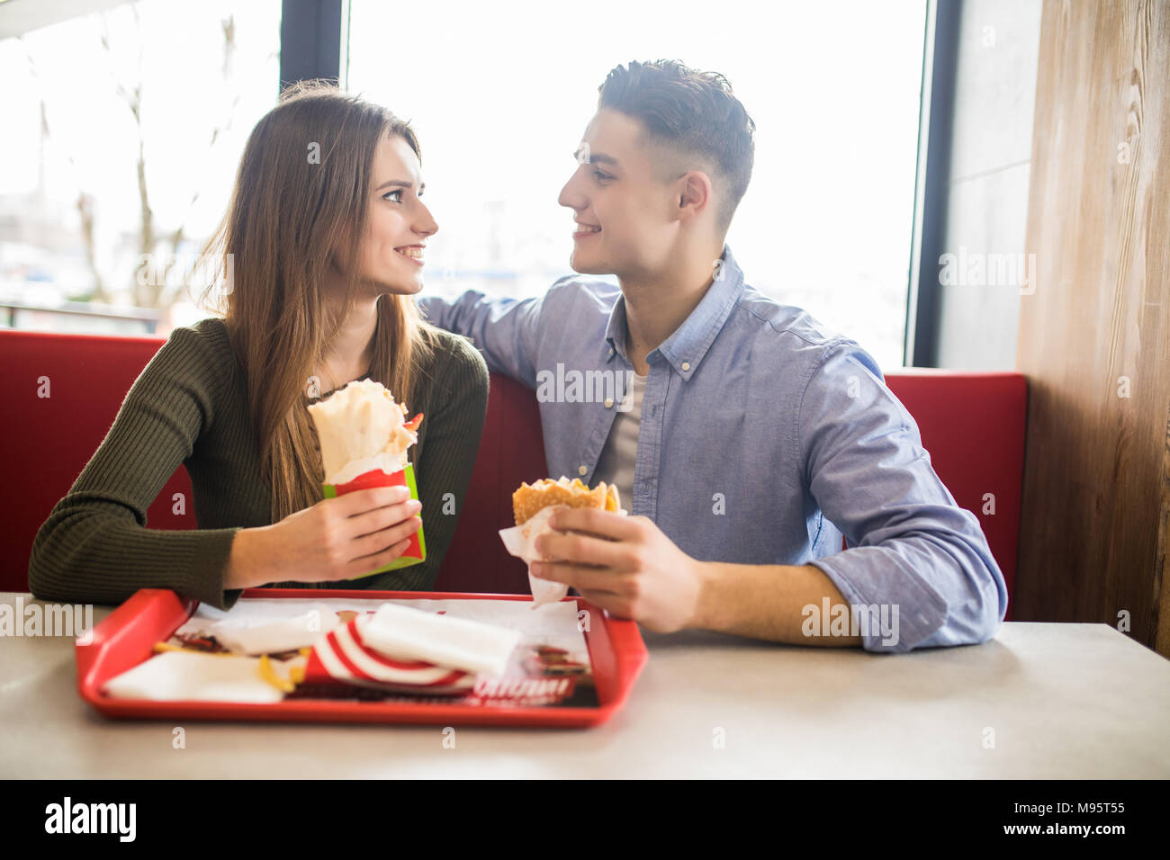 Cheerful Couple In Fast Food cafe Eating Burgers Stock Photo - Alamy