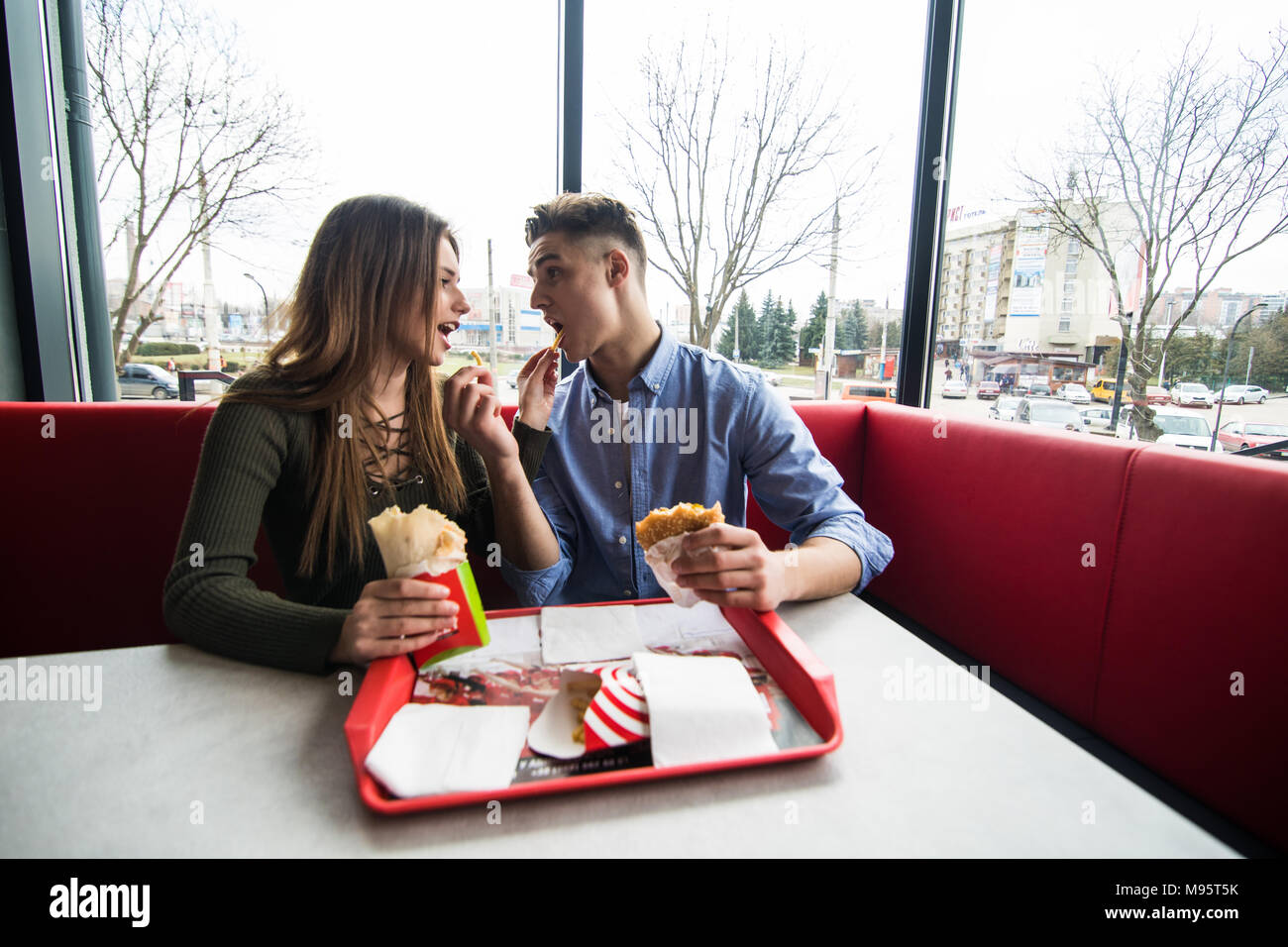 Cheerful Couple In Fast Food cafe Eating Burgers Stock Photo - Alamy