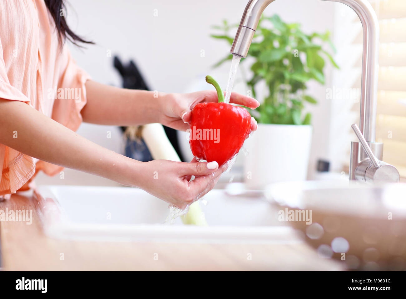 Young woman washing red bell pepper in modern kitchen Stock Photo - Alamy