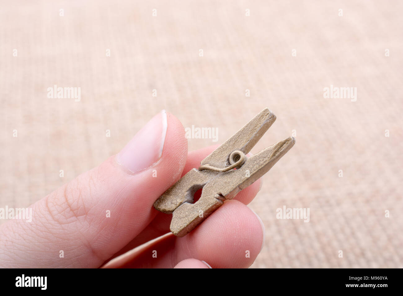 Hand holding a small wooden clothespin in hand Stock Photo - Alamy