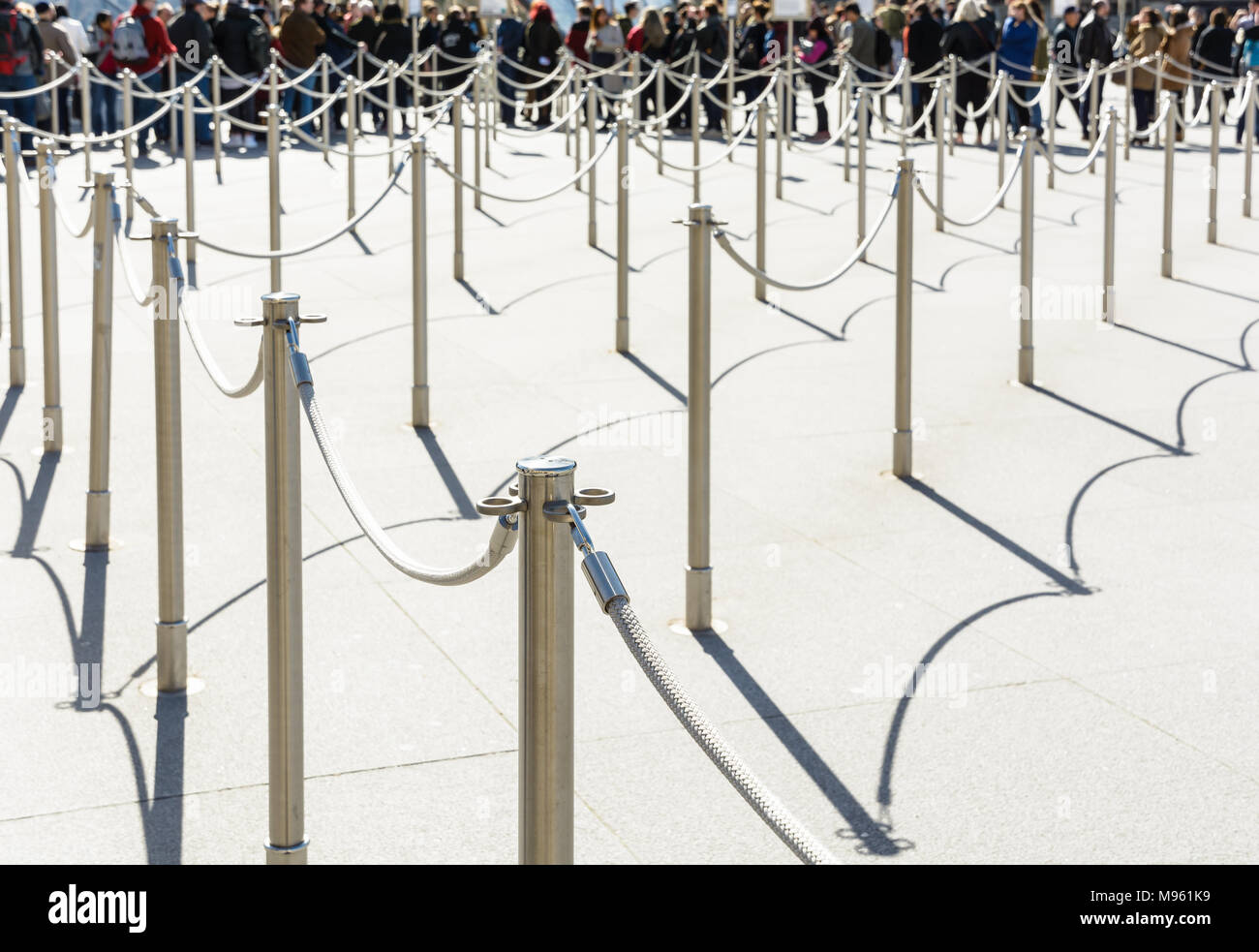 Stainless steel poles linked by grey ropes for queue control at the ...