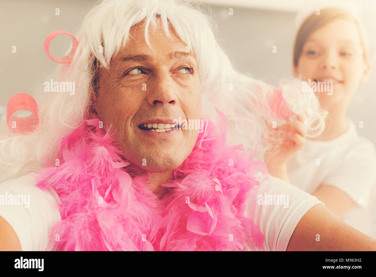 Nice thoughtful man wearing a wig and feather boa Stock Photo - Alamy