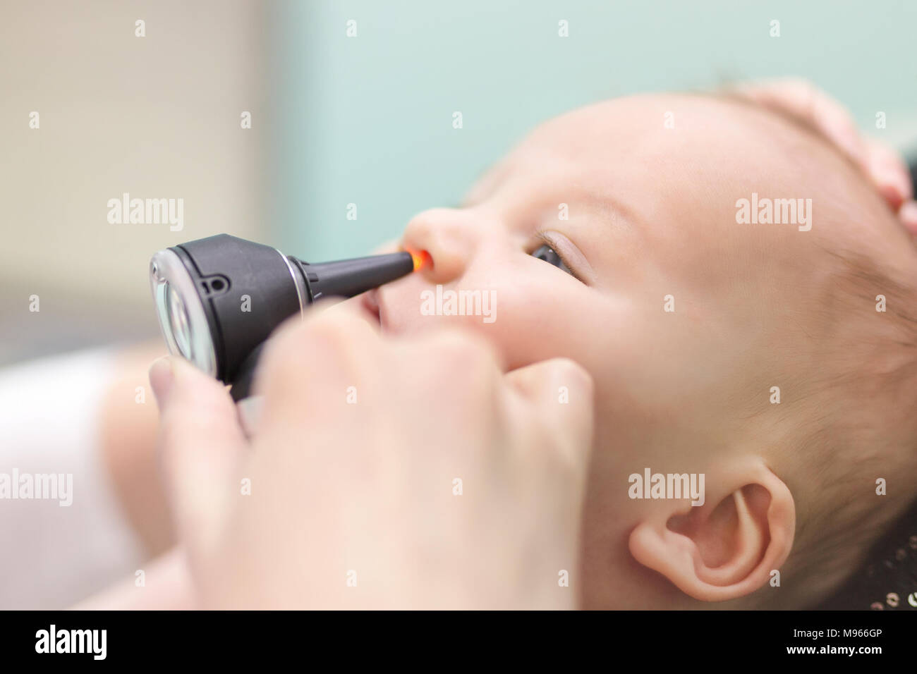 Infant in pediatric clinic. Close-up doctor's hand with modern otoscope ...