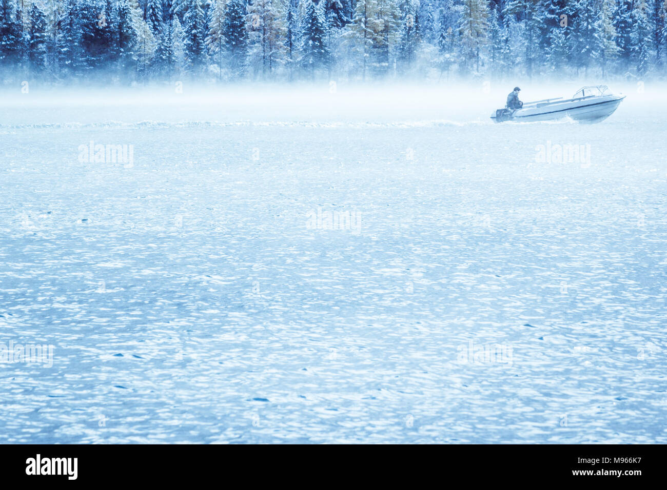 Motor boat sailing on the winter lake in the fog Stock Photo - Alamy
