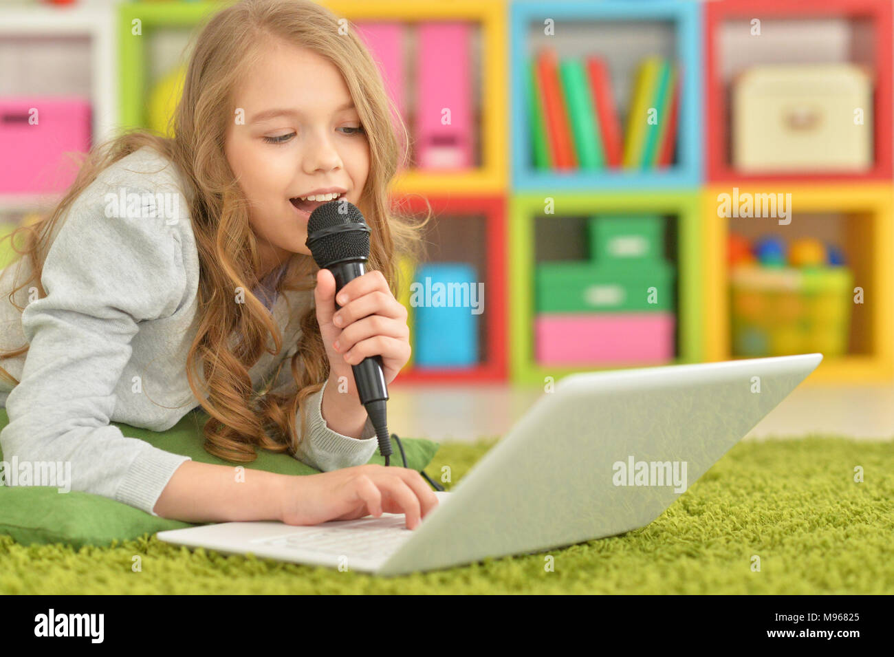 Adorable little girl using modern laptop and singing karaoke Stock ...