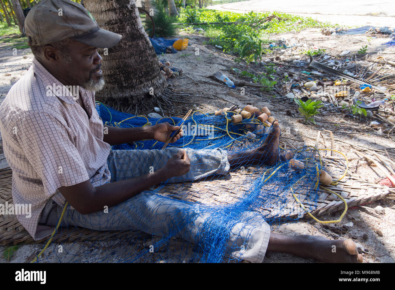 Fisherman on Uzi island, Zanzibar, mending fishing nets on the side of ...