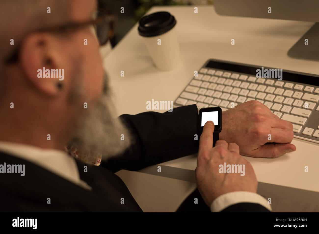 Business executive using smartwatch at desk Stock Photo - Alamy