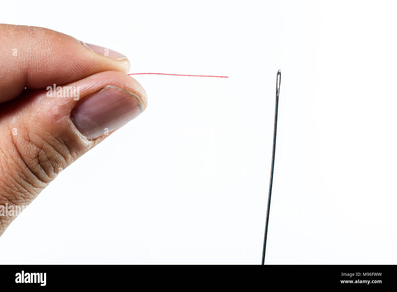 Hand Of Man Threading A Needle With Red Thread On White Background