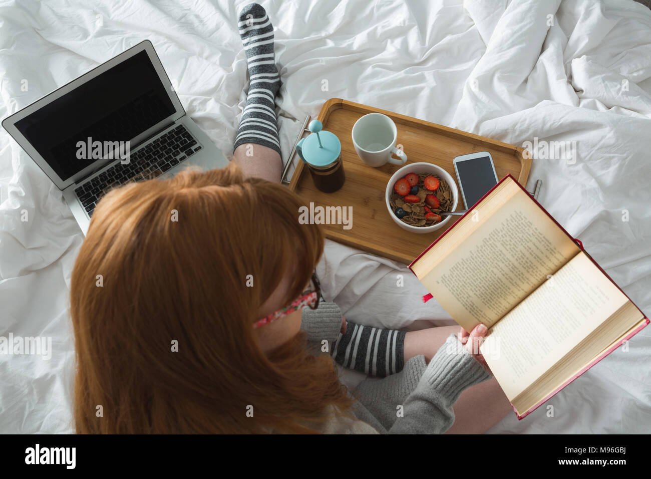 Woman reading a book in bedroom Stock Photo - Alamy