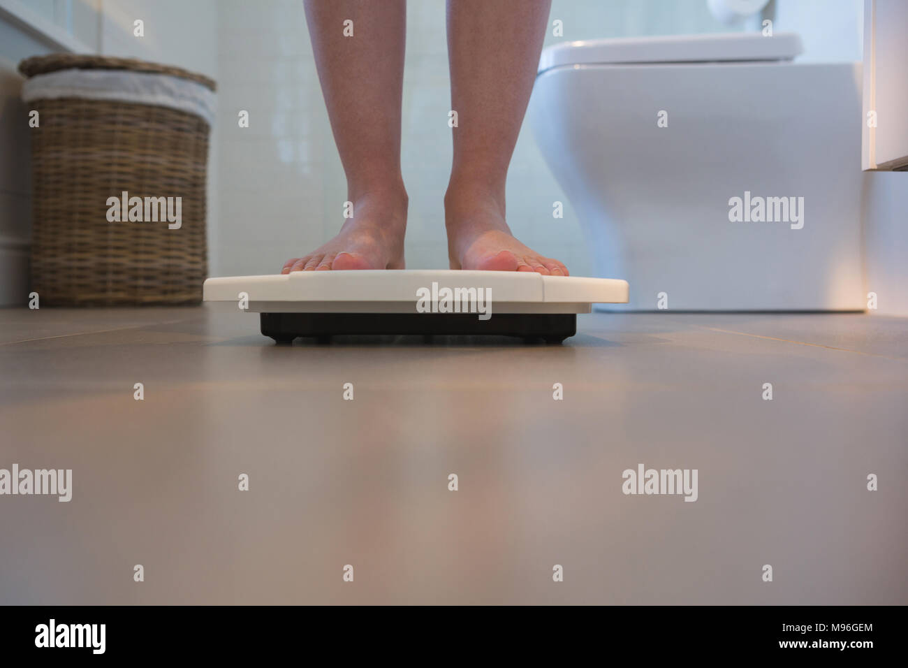 Woman checking her weight on weighing scales at home Stock Photo - Alamy
