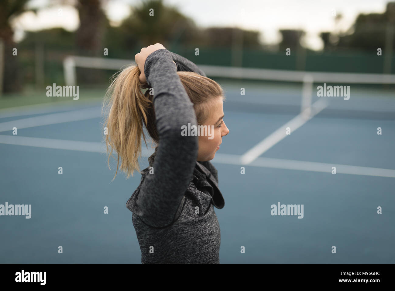 Woman standing with hands on hair in tennis court Stock Photo - Alamy