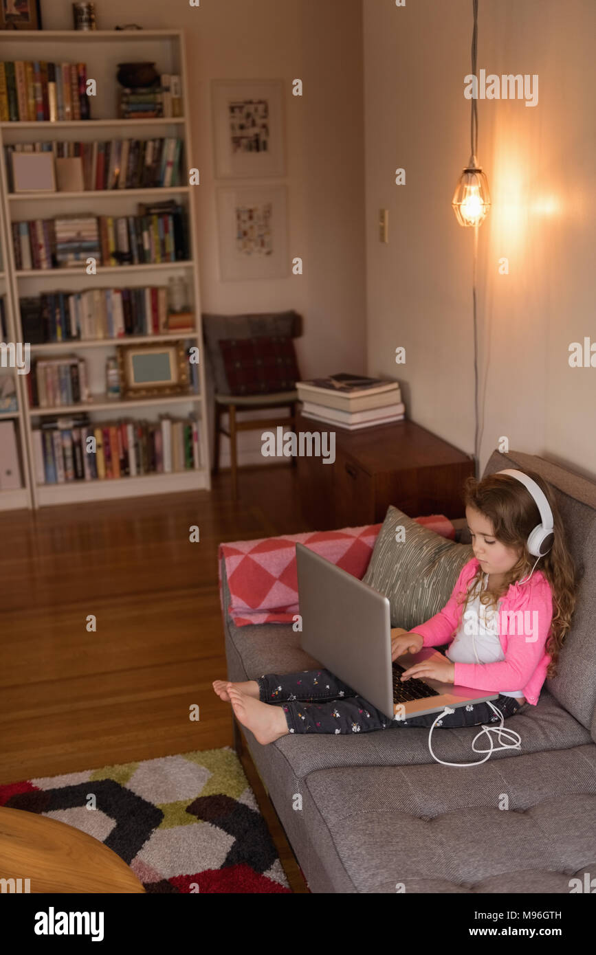 Girl using laptop on sofa in living room Stock Photo - Alamy