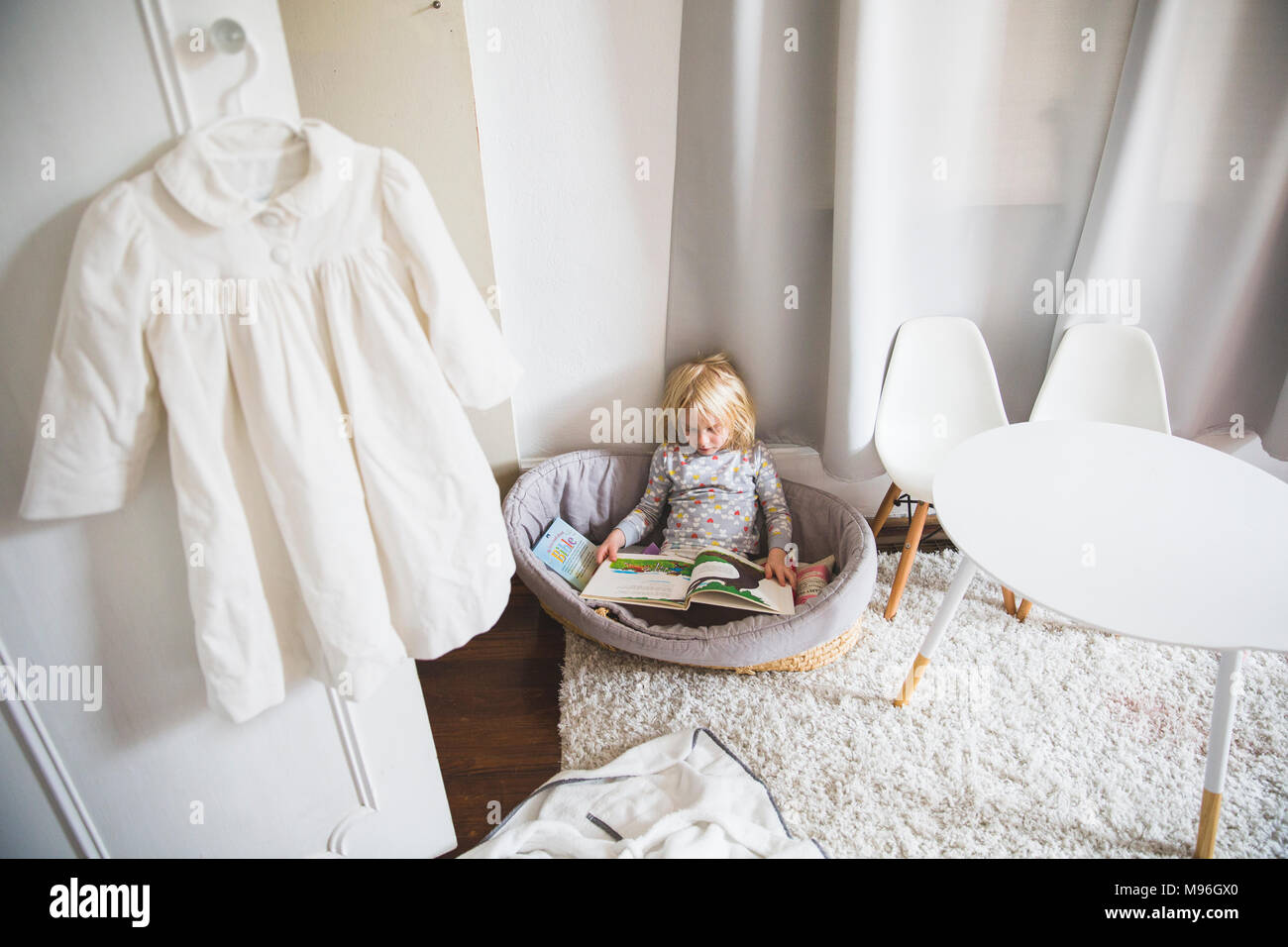 Girl sitting in playroom reading peacefully Stock Photo - Alamy
