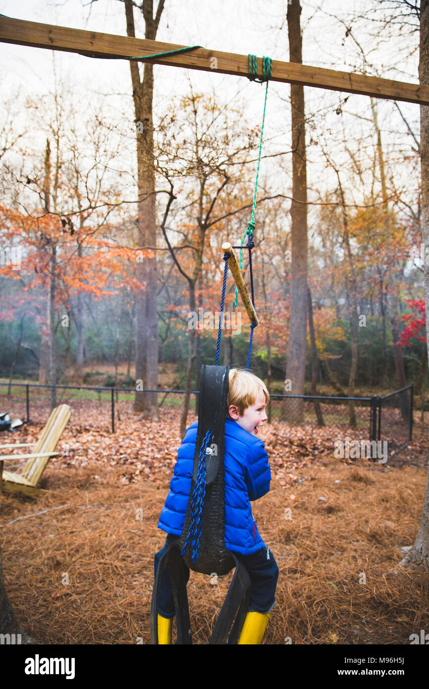 Boy in blue jacket swinging Stock Photo - Alamy