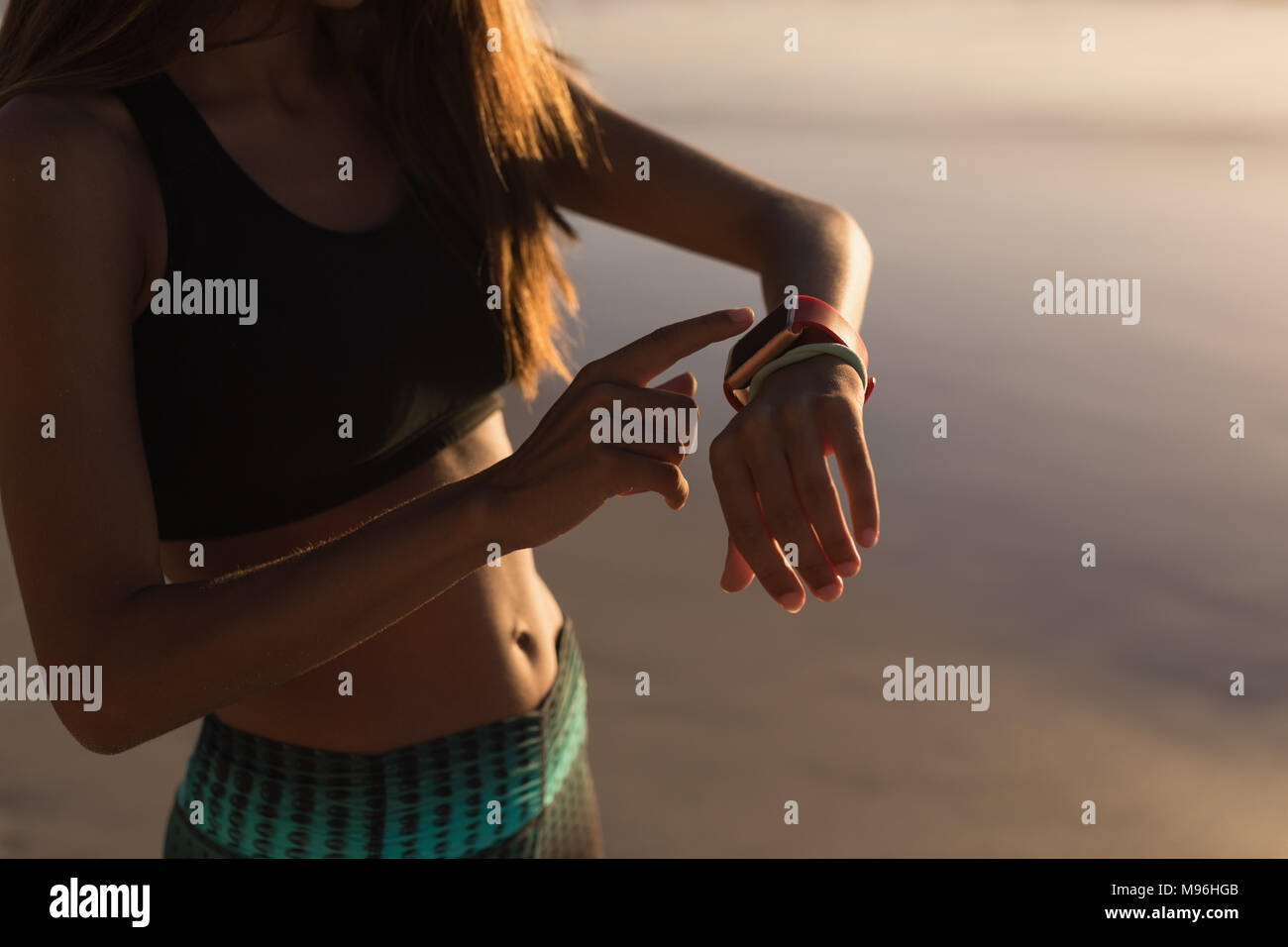 Fit woman using smartwatch in the beach Stock Photo - Alamy