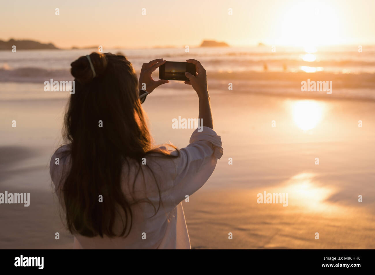 Woman clicking photo with mobile phone in the beach Stock Photo - Alamy
