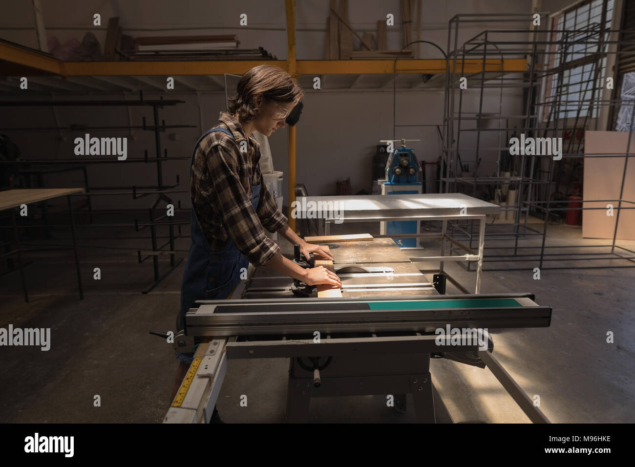 Female welder measuring a wooden piece in workshop Stock Photo - Alamy