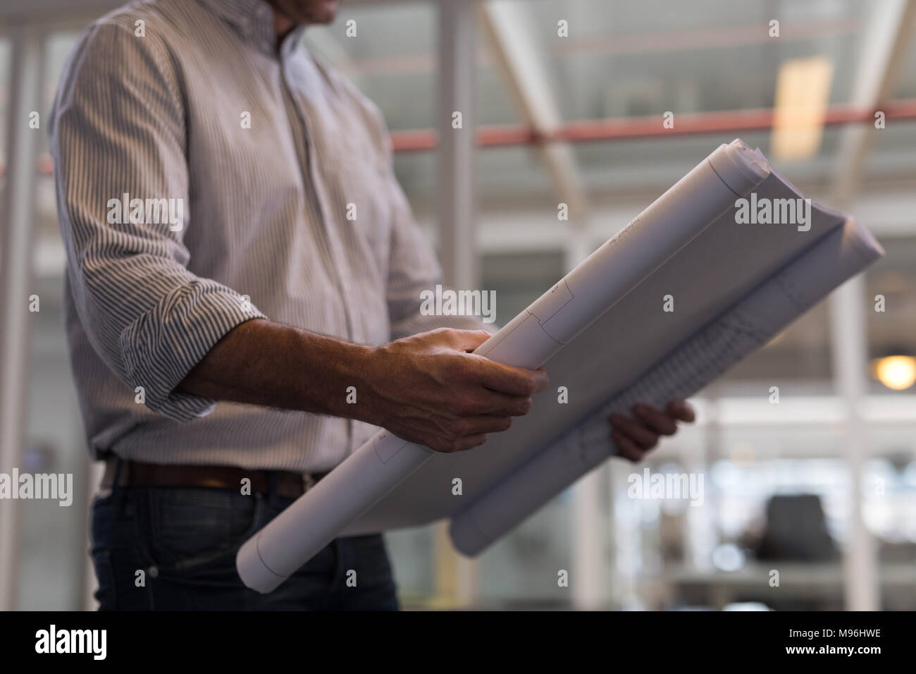 Male architect looking at blueprint in office Stock Photo - Alamy