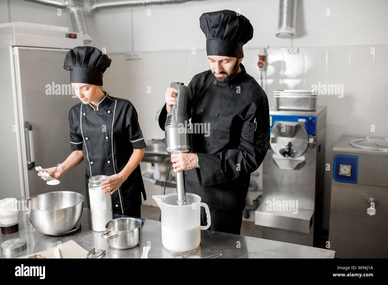 Chef cook with young woman assistant making ice cream together mixing ...