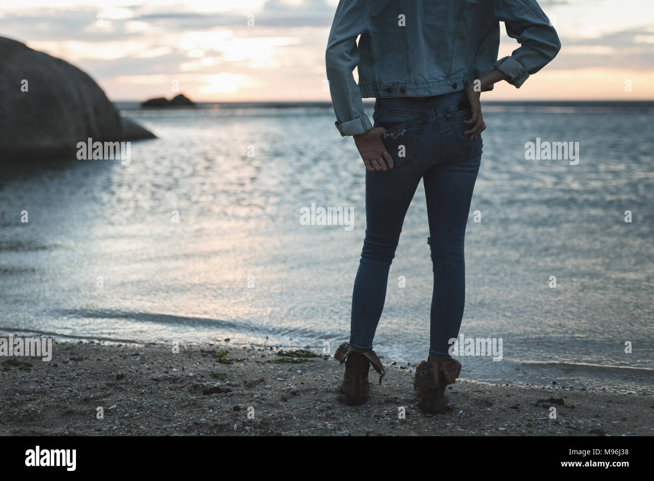 Woman looking at view on the beach at dusk Stock Photo - Alamy