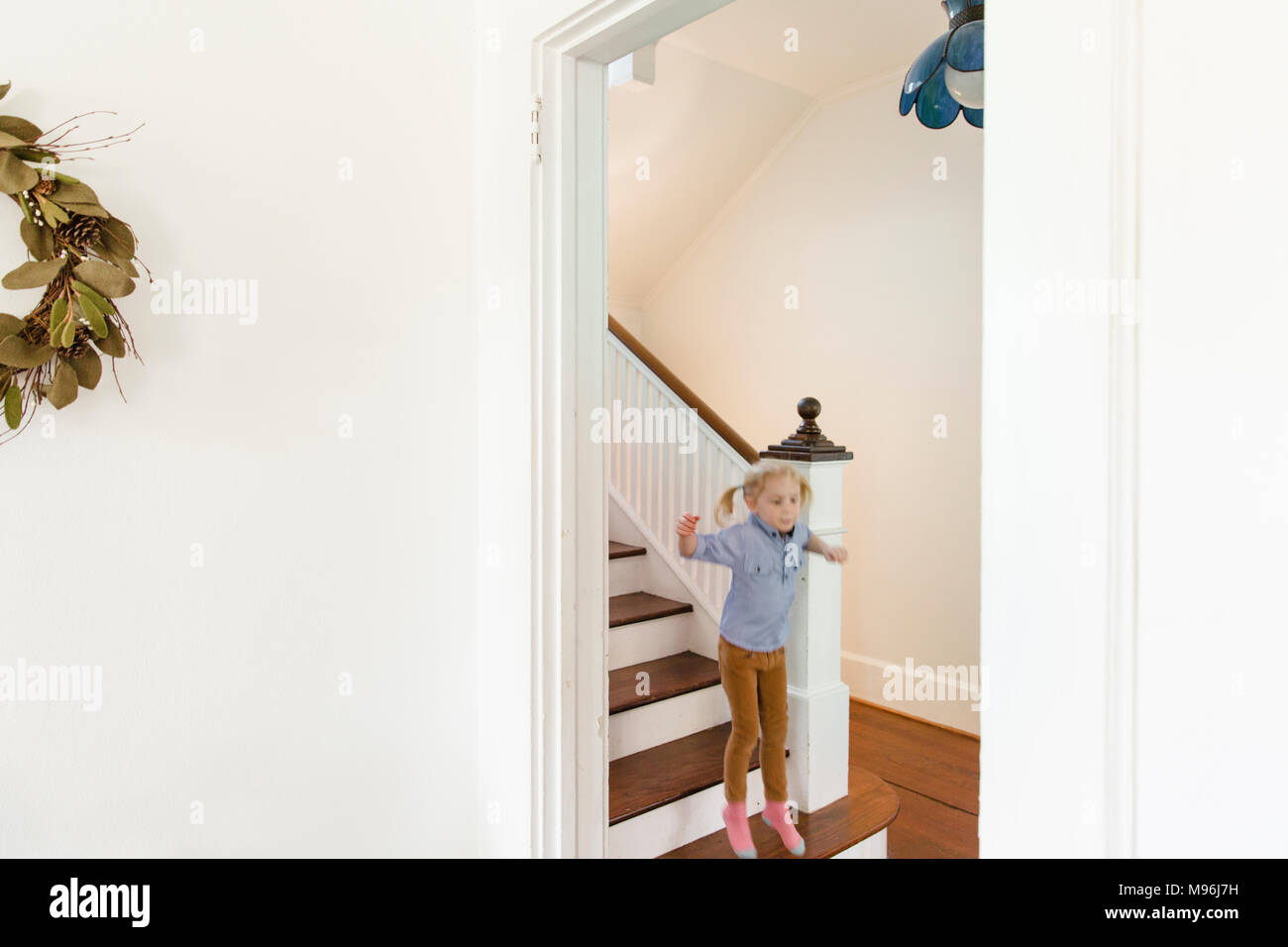 Girl jumping down steps of staircase Stock Photo - Alamy