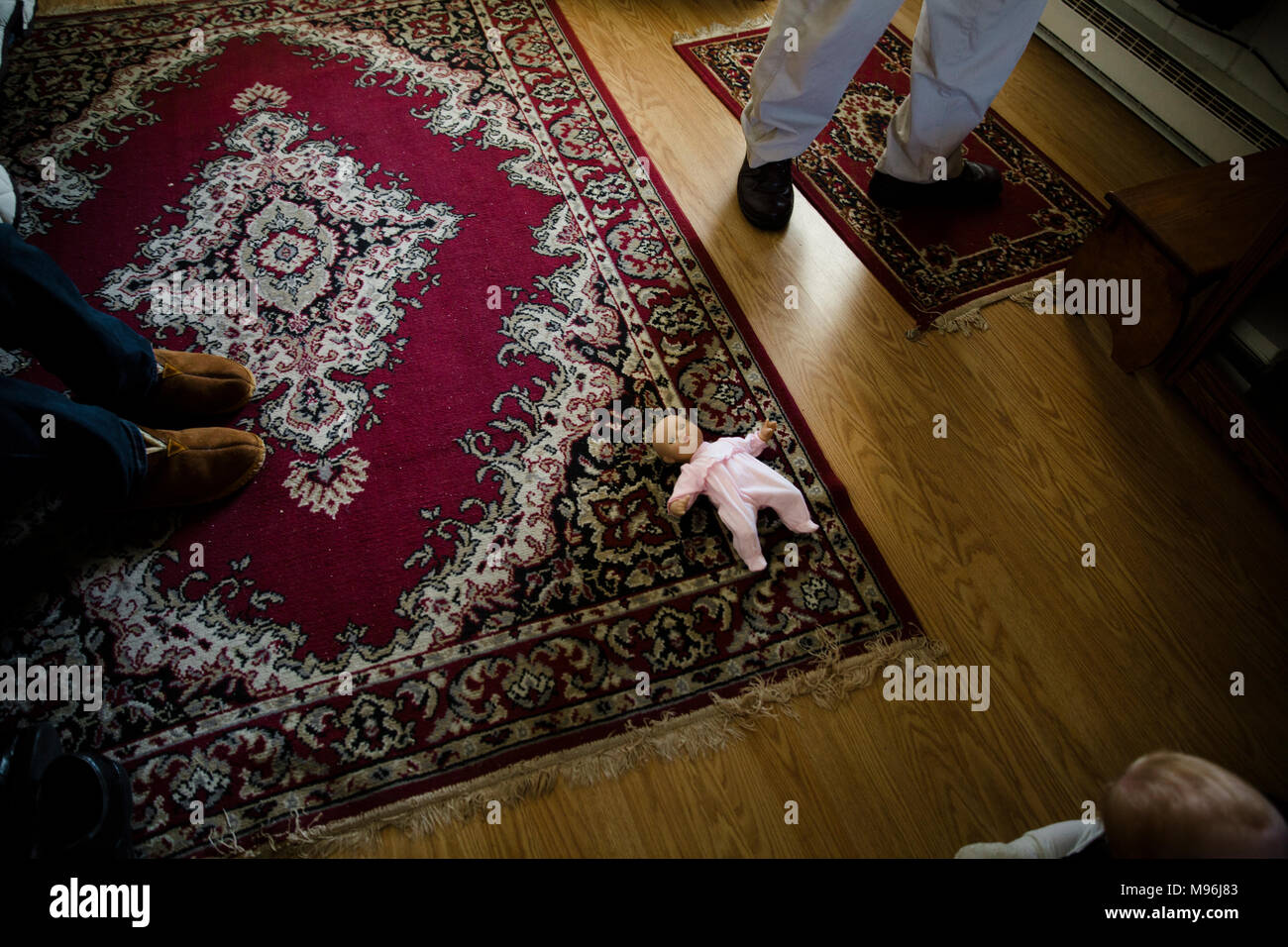 Baby doll laying on carpet with others standing around it Stock Photo ...