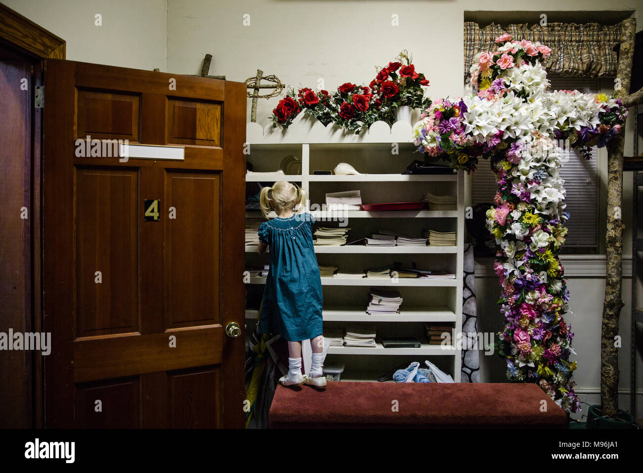 Girl looking through church shelves Stock Photo - Alamy