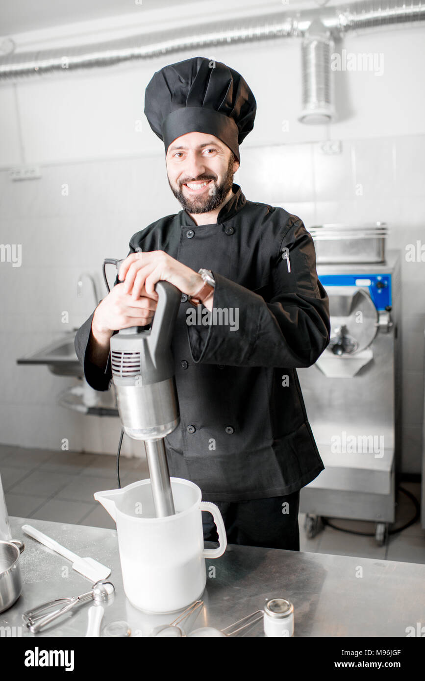 Portrait of a chef cook mixing with blender milk for ice cream ...