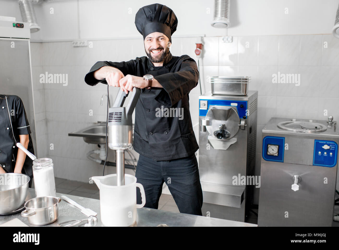Portrait of a chef cook mixing with blender milk for ice cream ...