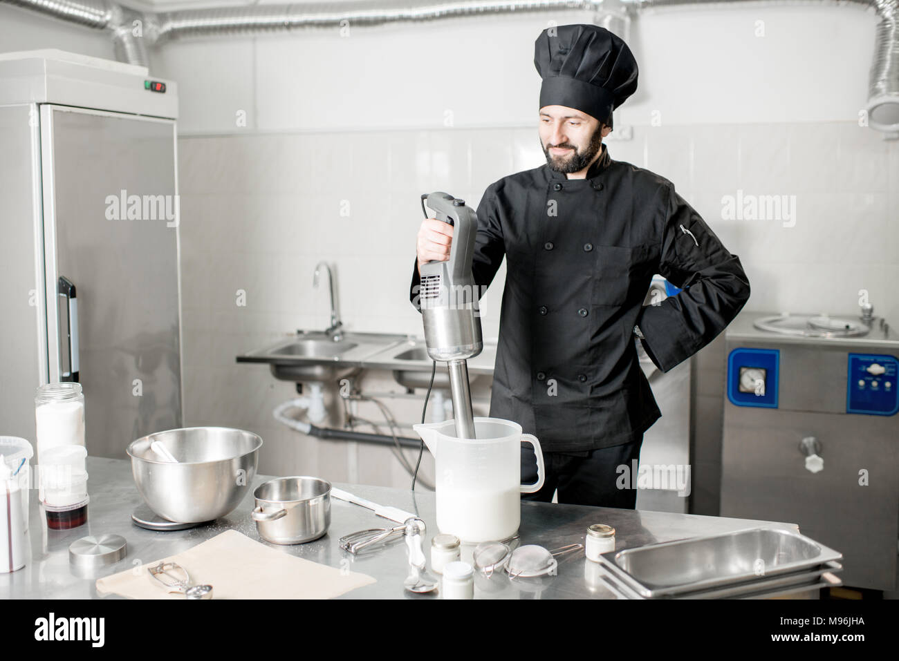 Portrait of a chef cook mixing with blender milk for ice cream ...