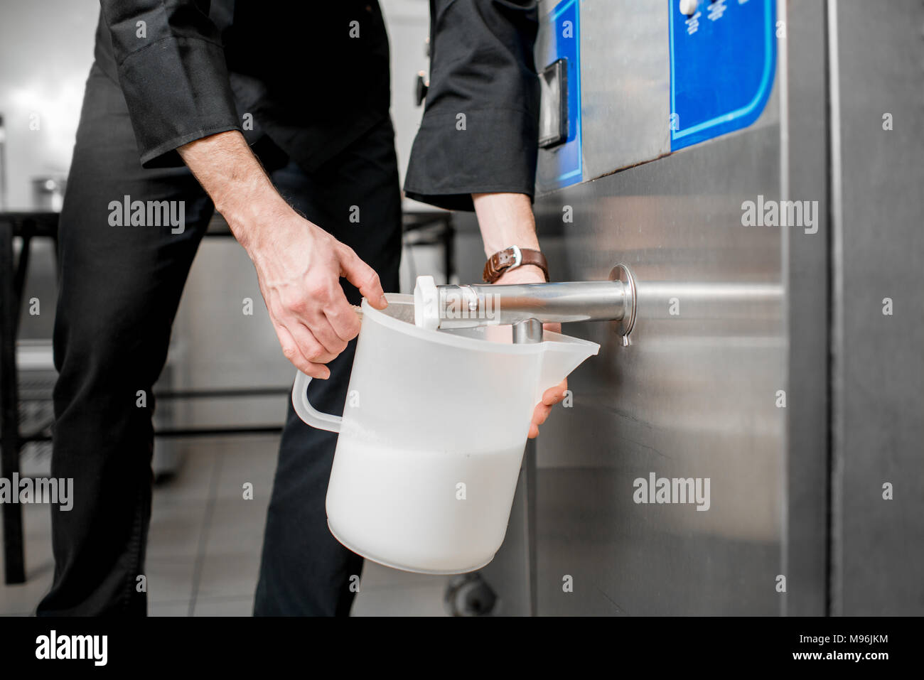 Chef pouring pasteurized milk into the jar for ice cream production ...
