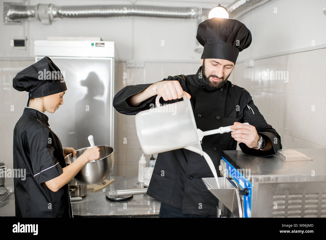 Chef pouring basis into the ice cream freezer machine in the small ...