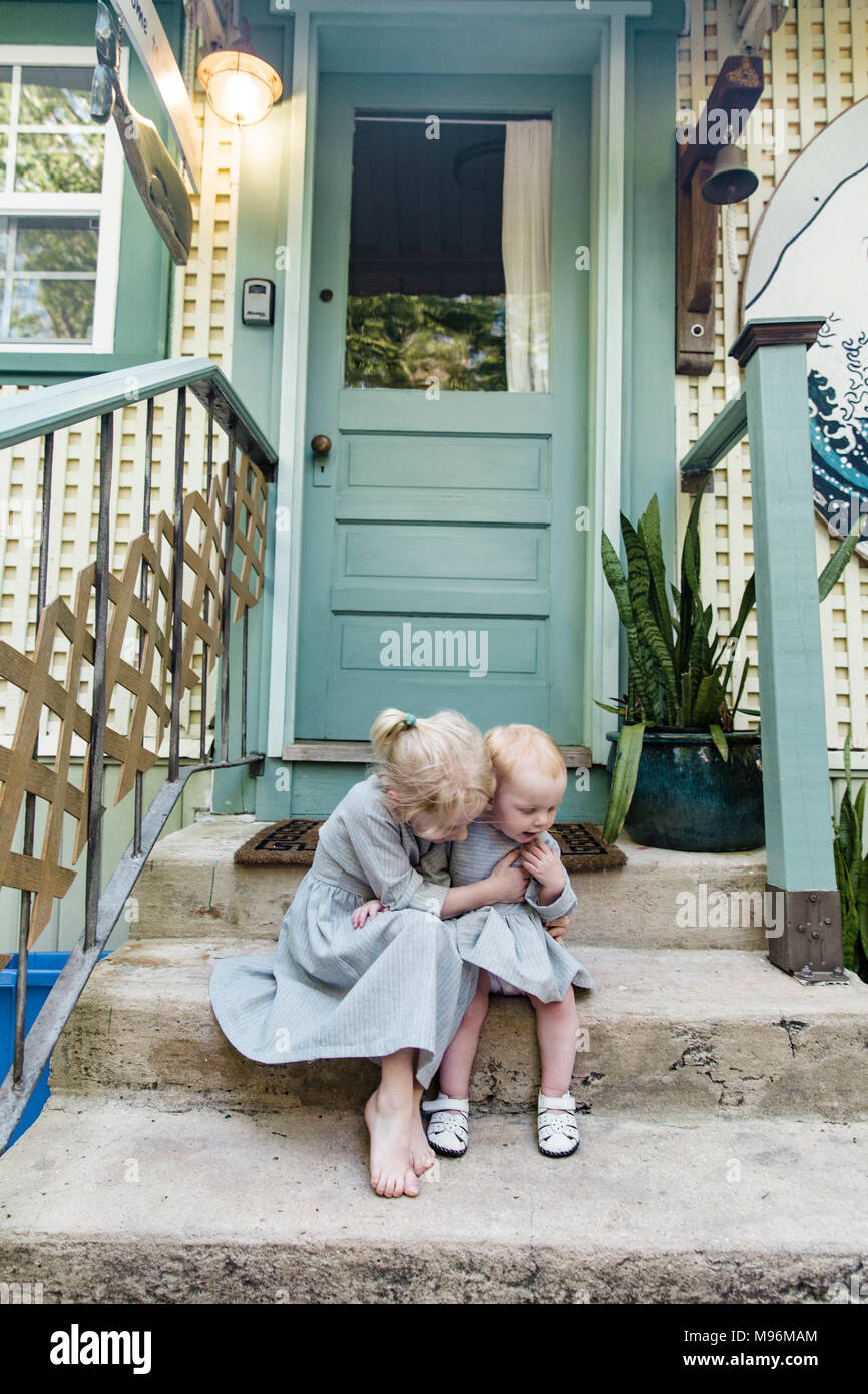 Girl and baby sitting outside on steps Stock Photo - Alamy