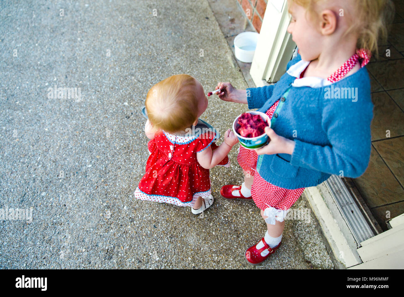 Girl feeding baby sister ice cream Stock Photo - Alamy