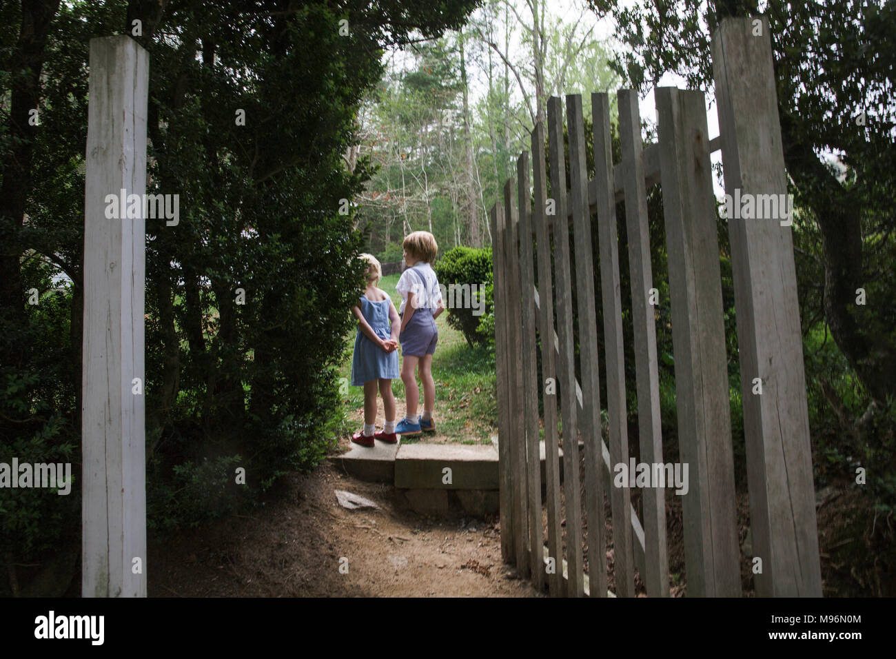 Two children looking into the distance with open gate Stock Photo - Alamy