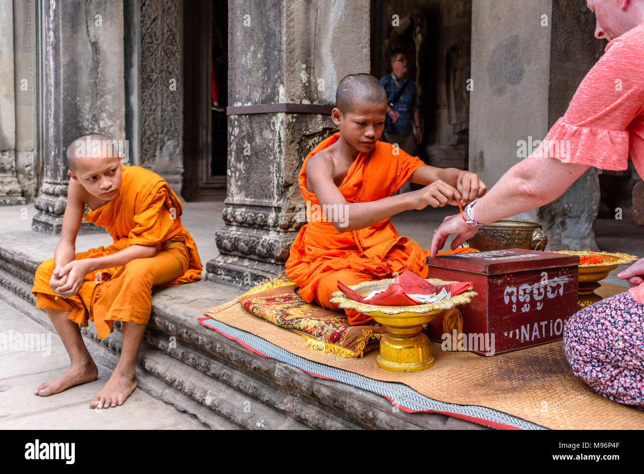 Monk wearing saffron robes says a prayer for a visiting tourist at the ...