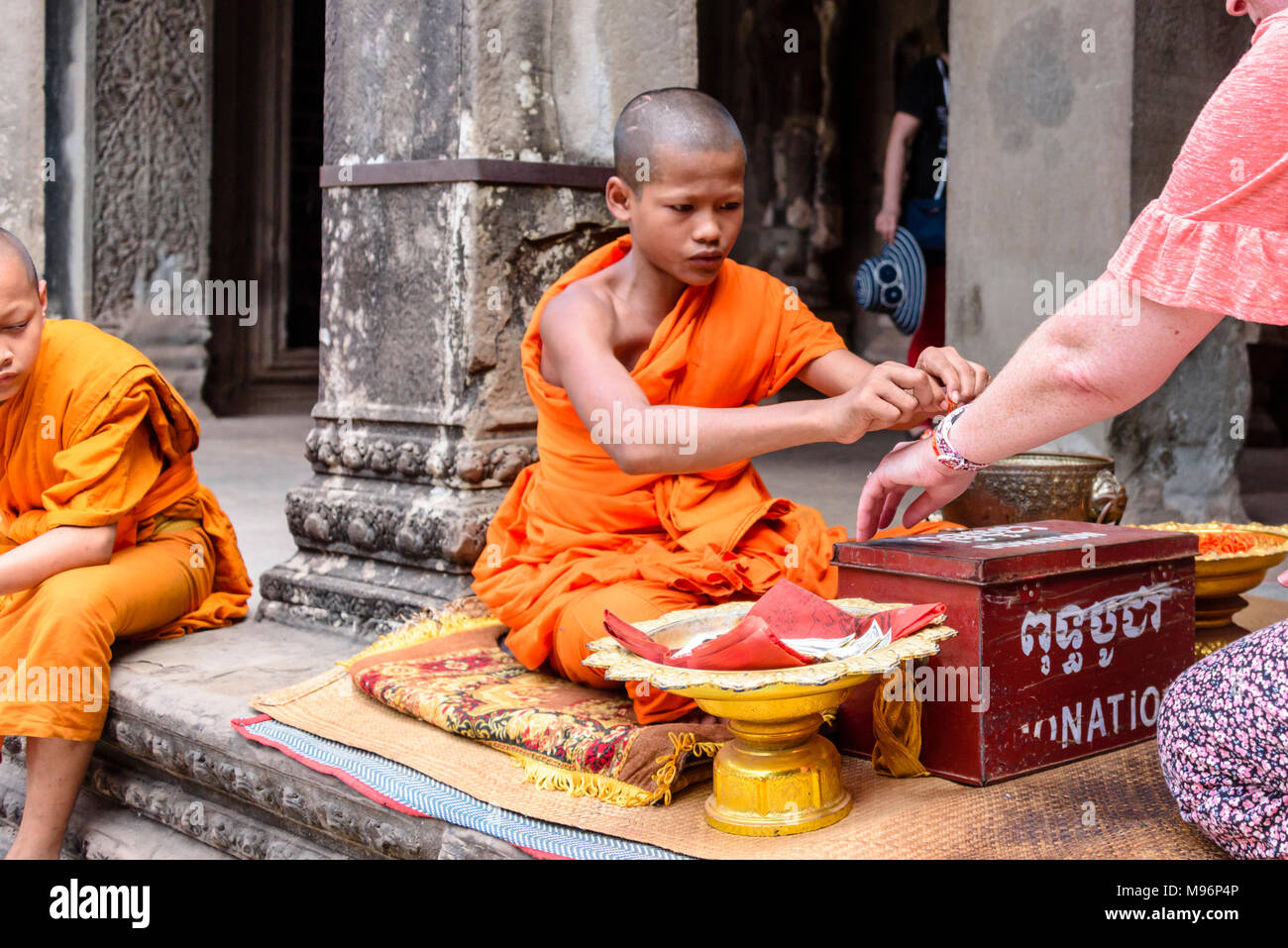 Monk wearing saffron robes says a prayer for a visiting tourist at the ...
