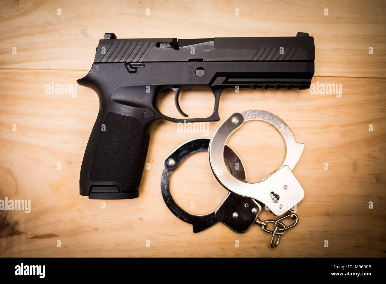 Hand gun with hand cuffs on wooden surface concept Stock Photo - Alamy